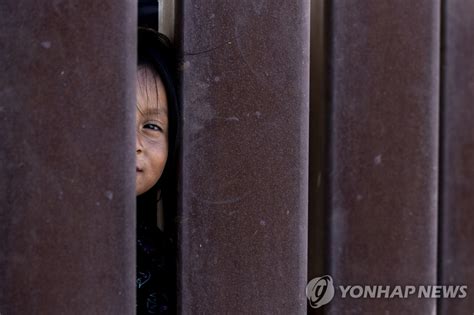 美국경 장벽 틈새로 얼굴 내미는 이민자 소녀 연합뉴스