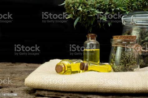 나무 및 검은색 배경에 투명한 유리 병에 버드 마리화나가 있는 오일 칸나비디올 Cbd 칸나비디올에 대한 스톡 사진 및 기타