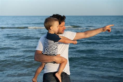 Premium Photo Father And Son Standing On Beach Against Sky