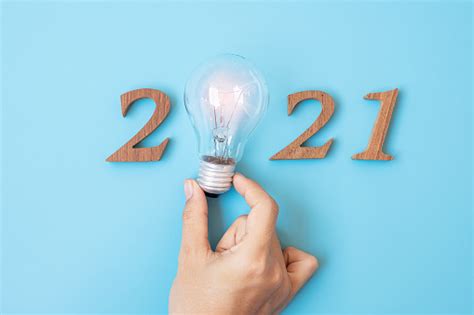 2021 년 새해 복 많이 받으며 전구와 나무 번호를 들고 있는 사업가와 함께 합니다 새로운 시작 아이디어 창의적 혁신 해상도