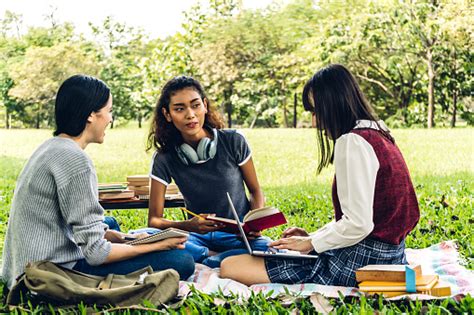 국제 학생 또는 십 대 들이 앉아서 학교에서 공원에서 함께 책으로 숙제를 하는 랩톱 컴퓨터를 사용 하는 웃는 그룹 교육 및 우정 개념 교육에 대한 스톡 사진 및 기타 이미지