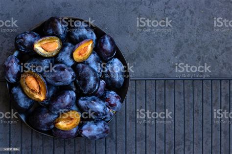 신선한 익은 파란색 전체와 어두운 회색 배경에 접시에 자두를 자른다 낮은 키 사진 하향식 보기 클로즈업 플랫 레이 구성 공간을 복사합니다 가을에 대한 스톡 사진 및 기타