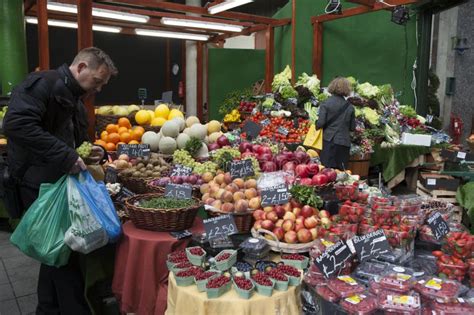 Неопознанный человек покупает фрукты и овощи на стойле в рынке города