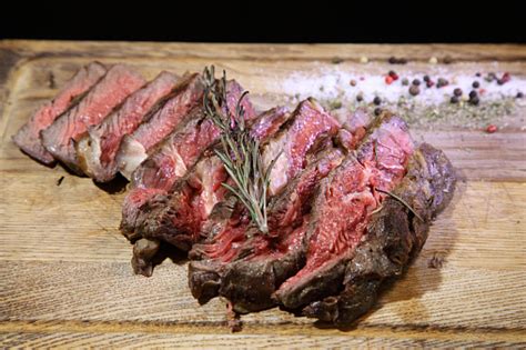 중간 크기의 스테이크는 소스와 조미료를 곁들인 나무 판에 조각으로 자릅니다 맛있는 스테이크 고급 요리에 대한 스톡 사진 및 기타