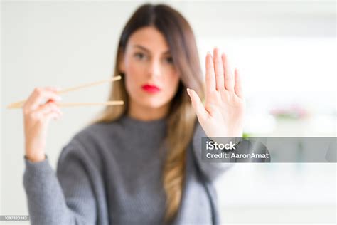 젊은 아름 다운 여 자가 집에서 아시아 젓가락 들고 열 심각 하 고 자신감 표현 방어 제스처 정지 표시를 하 고 손을 가정 생활에 대한 스톡 사진 및 기타 이미지 Istock