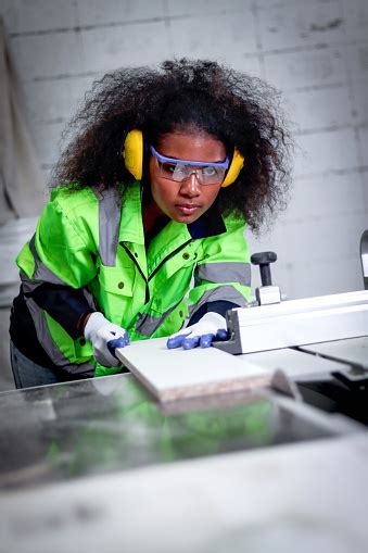 곱슬 머리를 가진 아프리카 산업 여성 노동자는 안전 조끼와 보호 헤드폰을 착용하고 목재 절단기로 작업하며 여성 엔지니어는 Cnc 목공 제조 가구 공장에서 일합니다 20 24