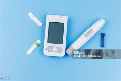 파스텔 블루 배경에 디지털 글루코프 랜싯 펜 일회용 바늘 및 테스트 스트립 맨 위 보기입니다 당뇨병 개념 개념에 대한 스톡 사진