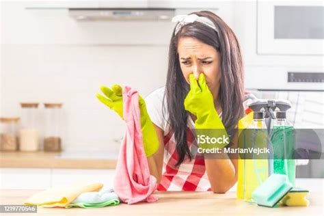 냄새 나는 헝겊을 들고 있는 여성에게는 손가락으로 코를 잡고 부엌 책상에 기대어 그녀를 둘러싼 청소 물건 불쾌한 냄새에 대한 스톡 사진 및 기타 이미지 Istock