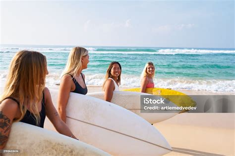 보드를 가진 여성 서퍼 그룹이 모래 해변을 따라 걷습니다 서핑 여행을 떠날 준비가 된 수영복을 입은 웃는 친구들 바다 파도에 의해 화창한 날 여성 서핑 모험 여행 건강한