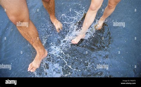 Unrecognizable Woman And Man Walking Barefoot Through A Puddle Stock
