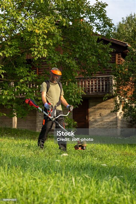 Side View Of A Gardener With Electrical String Grass Cutter Trimming Grass Eco Friendly Concept