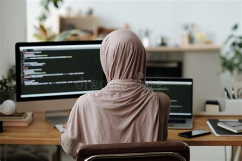 Rear View Of Muslim Female Programmer In Hijab Sitting In Front Of