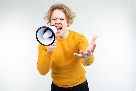 금발의 물결 모양의 남자는 흰색 스튜디오 배경에 라우드 스피커에 뉴스를 외치고 휴대용 마이크에 대한 스톡 사진 및 기타 이미지