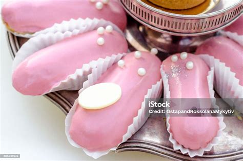 우아한 프랑스 과자 Pinc Eclairs 흰색 식용 공와 회사의 비문 또는 복사 공간 실버 플레이트에 대 한 화이트 초콜릿의 메달 장식 유약 0명에 대한 스톡 사진 및