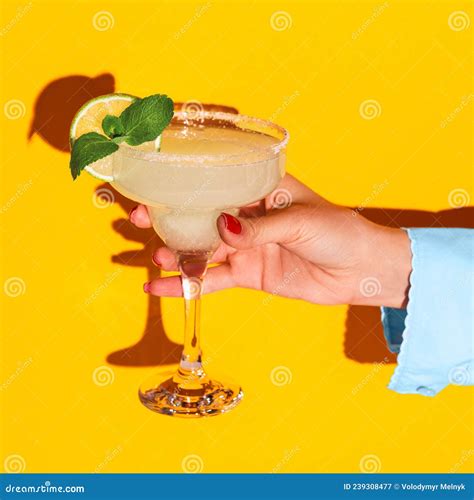 Female Hand Holding Glass With Margarita Cocktail On Bright Yellow Neon