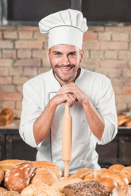 Free Photo Baker Standing Behind The Table With Variety Of Baked Breads
