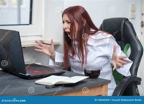 一个被注重的，恼怒的少妇坐在她的书桌并且是叫喊的在膝上型计算机以强烈的愤怒 库存图片 图片 包括有 动物 强烈 128445209