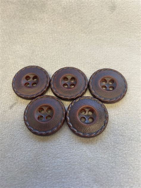 Four Brown Buttons Sitting On Top Of A White Cloth