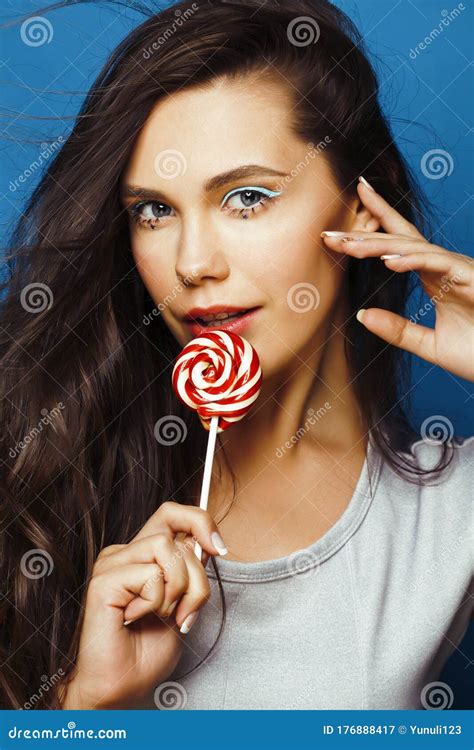 Young Pretty Adorable Brunette Woman With Candy Close Up Posing On Blue