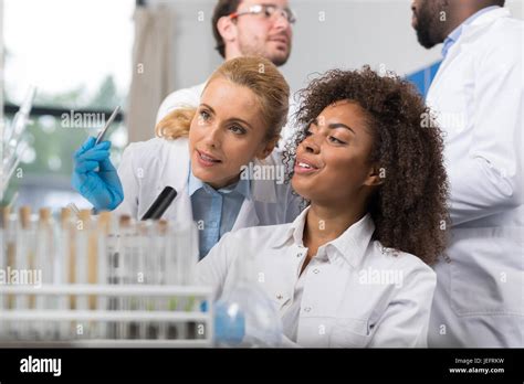 Two Female Scientist Examine Sample Working In Modern Laboratory Group