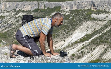An Adult Man On The Edge Of The Gorge Side View Is On All Fours Man