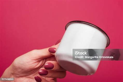 여성의 손은 분홍색 배경에 검은 가장자리가있는 에나멜 머그잔 흰색을 들고 있습니다 텍스트 또는 브랜딩을 위한 장소입니다 개념에 대한 스톡 사진 및 기타 이미지 Istock