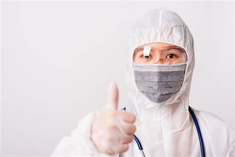 Ppe 유니폼을 입은 여성 의사 또는 간호사는 실험실에서 얼굴 마스크 보호 를 입고 손가락 엄지 손가락을 위로 유지합니다