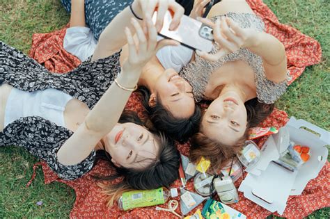 공원의 풀밭에 누워있는 스마트 폰으로 셀카를 찍는 세 명의 젊은 아시아 여성 친구 아시아인에 대한 스톡 사진 및 기타 이미지