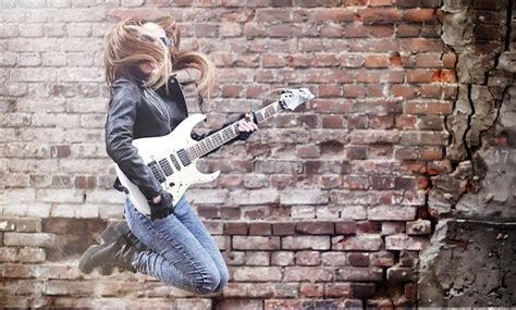 Rockero hermosa joven con guitarra eléctrica canta una chica músico de rock con una chaqueta de