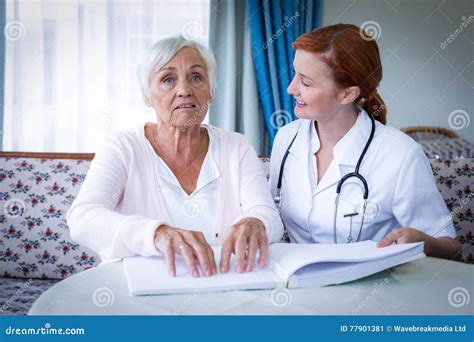 Female Doctor Helping A Blind Patient In Reading The Braille Book Stock