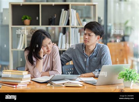 Two Asian Students Learning Together And Tutor Together At Cafe And