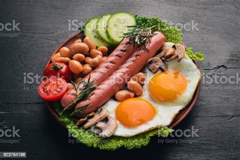 영어 아침 식사입니다 튀긴 계란 소시지 베이컨 콩 토스트 토마토 돌 테이블에 커피 컵 텍스트를 위한 공간 평면도 가득 찬에 대한