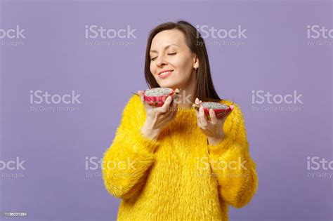 모피 스웨터에 예쁜 젊은 여성이 피 야 하 야의 Halfs 스니핑 보라색 파스텔 배경에 고립 용 과일을 폐쇄 유지 합니다