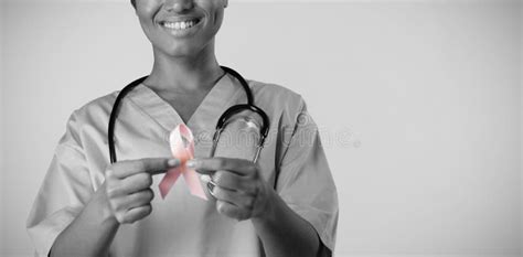 Smiling Nurse Holding Breast Cancer Awareness Pink Ribbon With Both