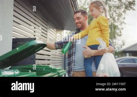 Happy Father Holding A Young Girl And Going To Throw Away An Empty