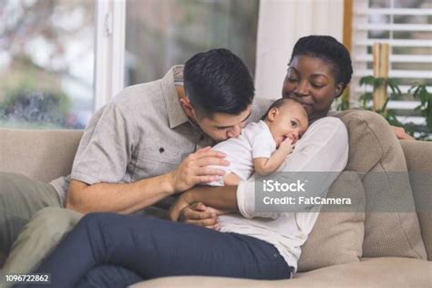 그들의 거실에 있는 소파에 그들의 유아 딸과 함께 안 아 Interracial 커플 신생아에 대한 스톡 사진 및 기타 이미지