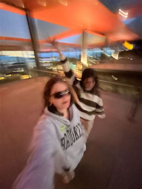 Two Girls Are Posing For The Camera With Their Arms In The Air And One