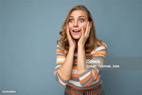사진 의 젊은 놀라게 꽤 좋은 금발 곱슬 여자 진지한 감정 입고 캐주얼 스트라이프 풀오버 고립 된 블루 배경에 무료 공간