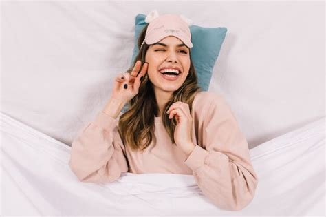 Femme heureuse souriante en pyjama couché dans son lit Photo Gratuite
