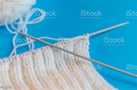 양모 원사에서 스카프를 뜨개질 단계별로 뜨개질을 배우다 파란색 배경에 흰색 실로 만든 스카프 홈 스쿨링 0명에 대한 스톡 사진