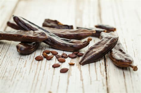 Carob 포드입니다 건강 한 유기농 Carob 콩 깍 지 고 흰색 나무 테이블에 씨 건강 한 식사 음식 배경입니다 로커스트