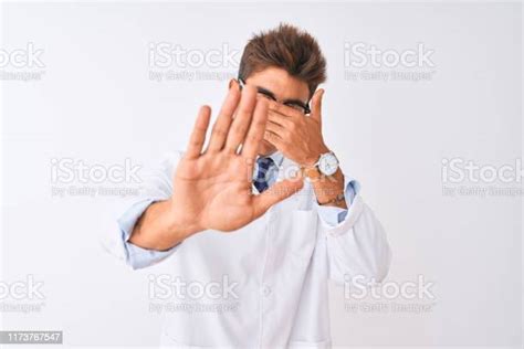 젊은 잘생긴 Sciencist 남자 안경과 코트 위에 고립 된 흰색 배경 에 손을 덮고 슬프고 두려움 표현으로 중지 제스처를하고