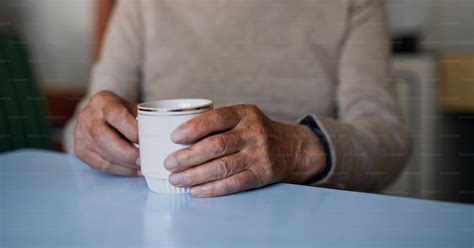 차 한 잔을 들고 집에 실내에 앉아 쉬고 있는 알아볼 수 없는 노인 사진 Unsplash의 컵 이미지