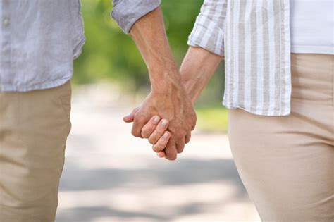 야외에서 함께 걷는 동안 손을 잡고 사랑하는 성숙한 커플의 클로즈업 샷 프리미엄 사진
