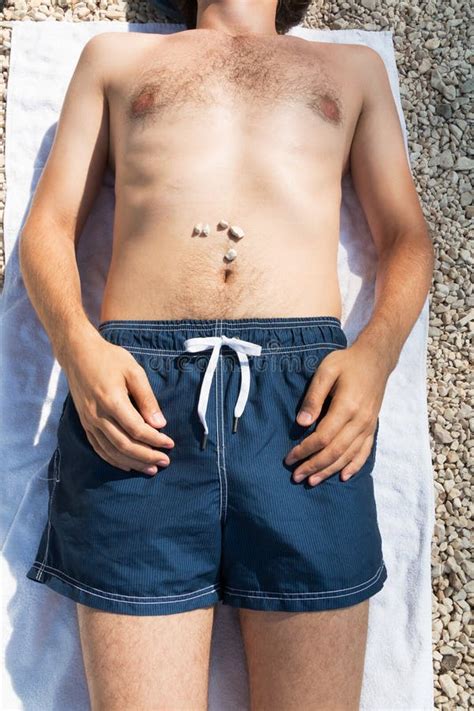 Um Homem Novo Considerável No Short Azul Que Dorme Em Uma Praia Seixoso