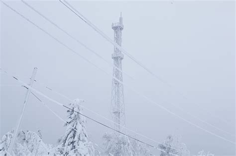 겨울 하늘을 배경으로 산 꼭대기에 있는 눈 덮인 숲 위에 서리가 내린 셀타워와 전선 0명에 대한 스톡 사진 및 기타 이미지