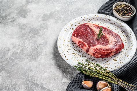 도마에 조미료와 신선한 고기 Ribeye 스테이크 갈비 눈 쇠고기 스테이크 회색 배경 맨 위 보기입니다 복사 공간 갈비 음식에