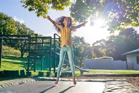 Carefree Girl Jumping On Trampoline In Sunny Backyardの写真素材 Fyi07852106
