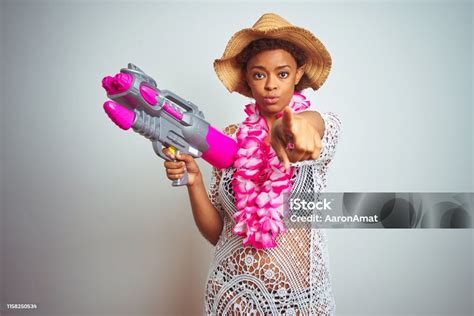 젊은 아프리카 계 미국인 여성 Afro 머리 를 입고 꽃 하와이 레이와 물 총 카메라와 당신에 게 손가락으로 가리키는 손 기호 앞에서 긍정적이 고 자신감 제스처 가리키기에