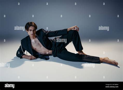 Stylish Man In Suit With Pearls And Hairy Chest Posing On Dark Grey